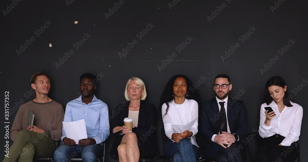 Serious mixed race different ages business people sitting in row line ...