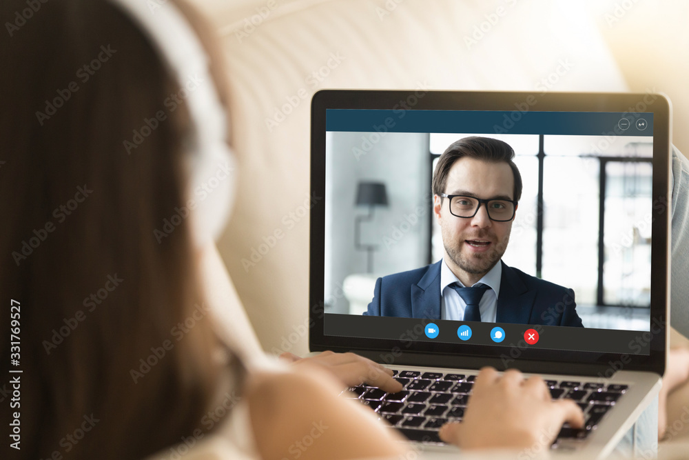 Pc screen view over woman shoulder, female wear headphones sitting on ...
