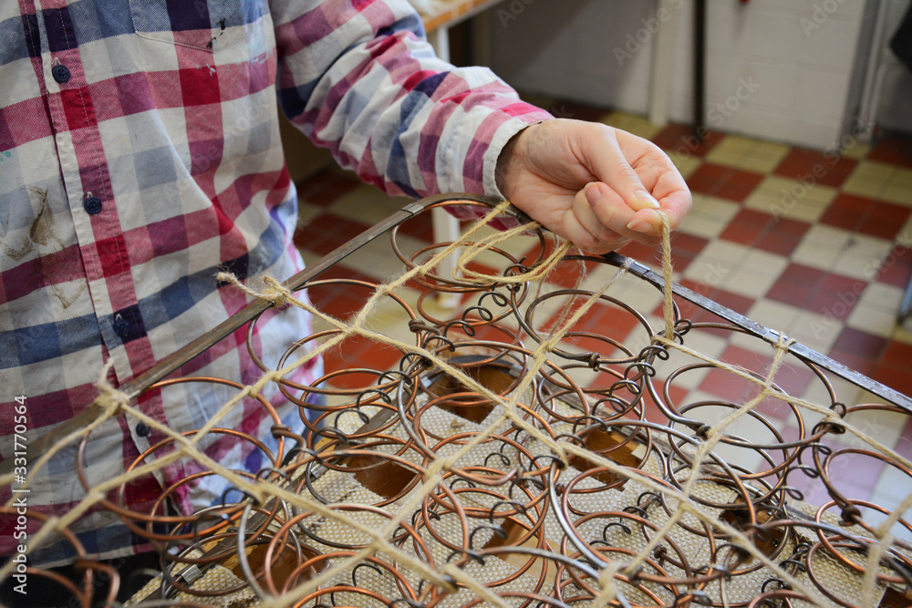 Upholstery springs. Upholstery worker tying old srpings. Upholstery ...