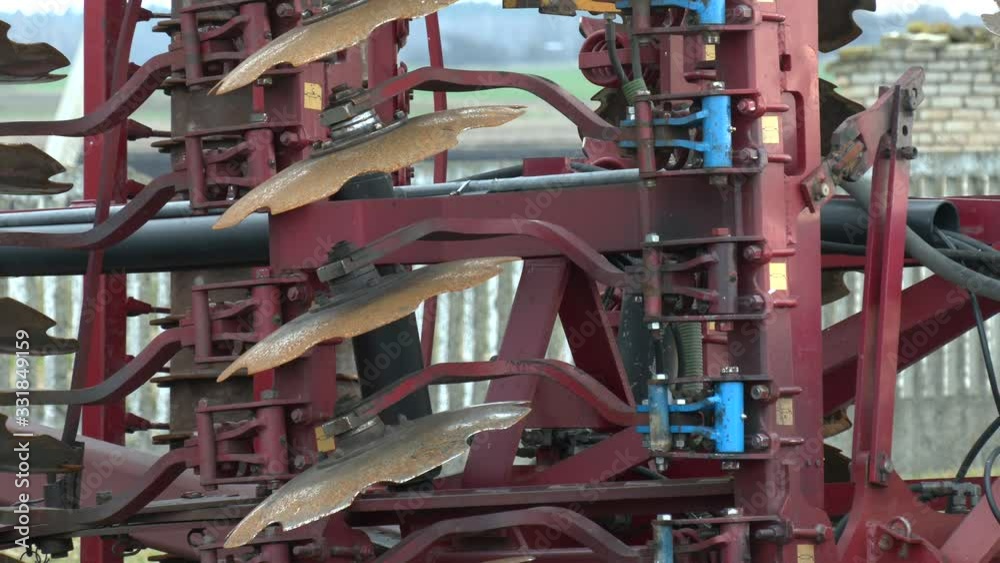 Rusty blades of farm equipment in a field on a rainy day. The tractor ...
