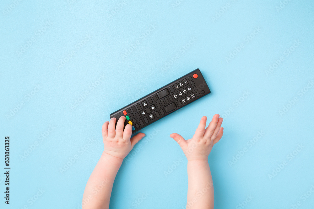 Infant hand reaching after remote control on light blue table ...