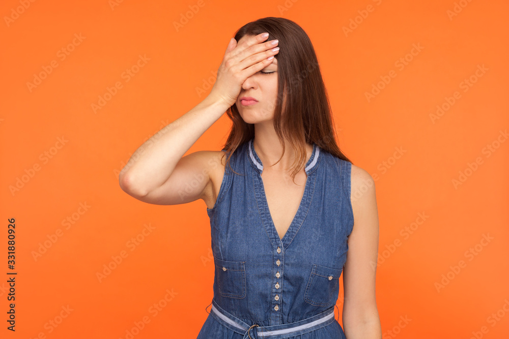 Facepalm. Distressed regretful brunette woman in denim dress covering ...