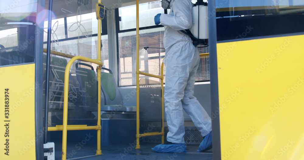 HazMat team in protective suits decontaminating public transport, bus ...
