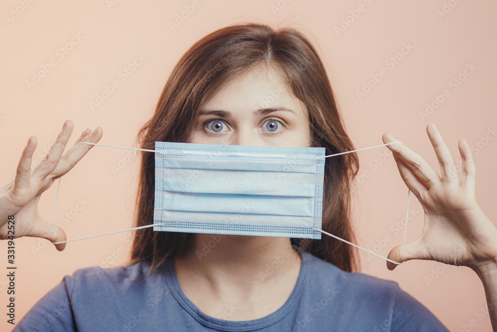 Portrait of young woman showing opened medical flu mask covering face ...