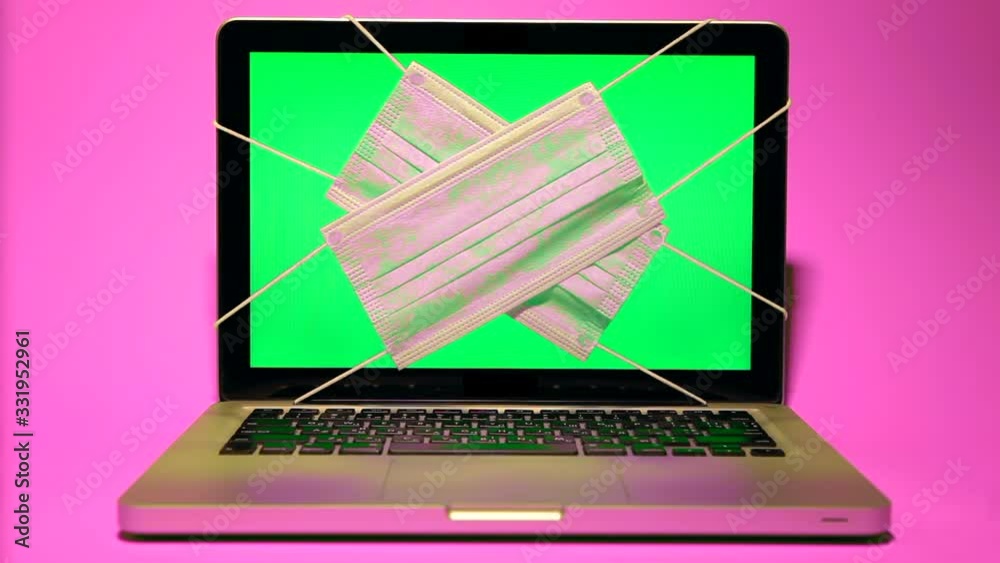 The laptop is on a purple background with surgical masks on the monitor ...