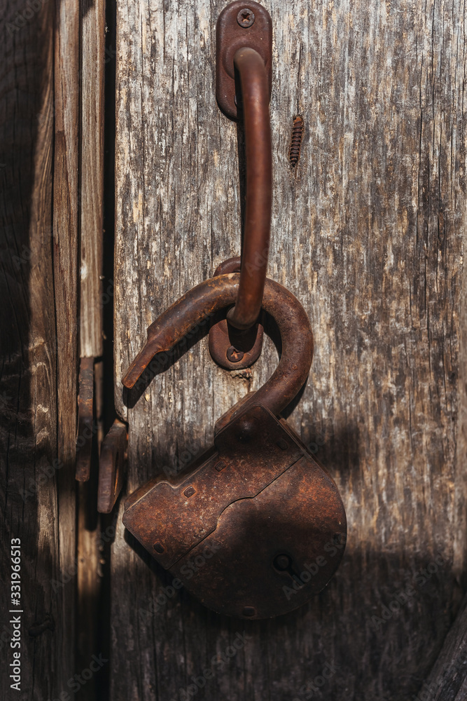 Old rusty barn lock. Open lock on the metal handle of a wooden door ...