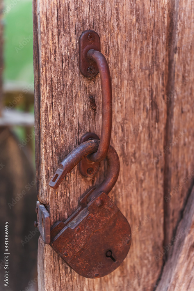Old rusty barn lock. Open lock on the metal handle of a wooden door ...