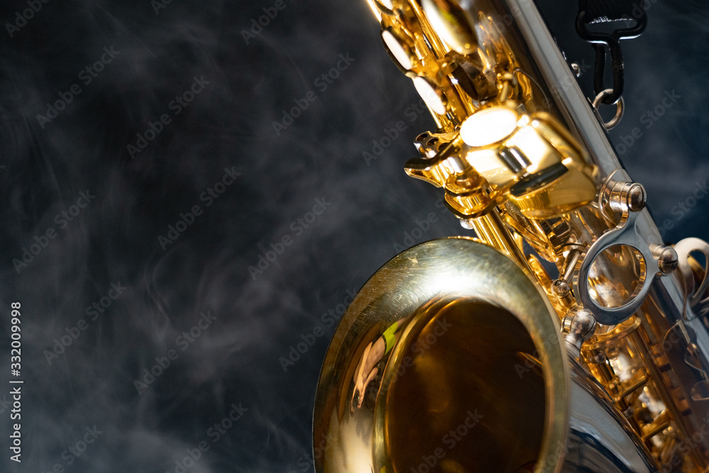 Poster Golden shiny alto saxophone on black background with smoke ...