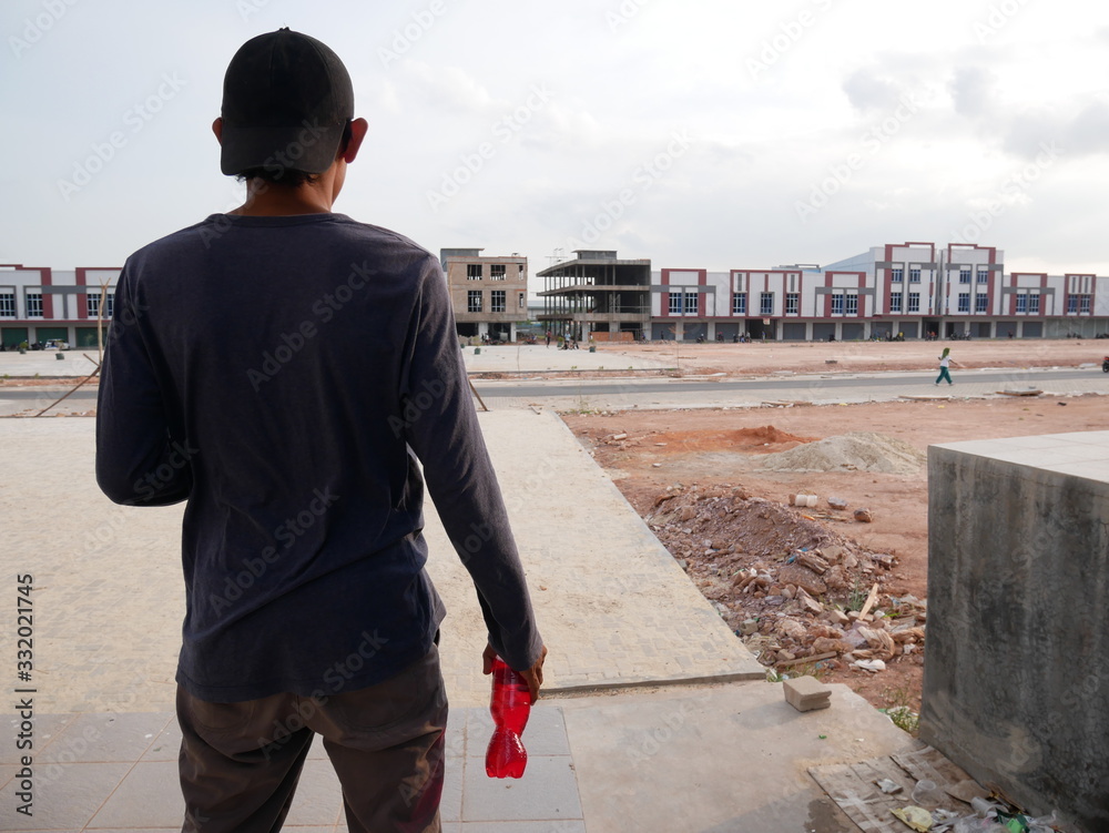 Back view of man with bottle of soda,see the building in front.drinking ...