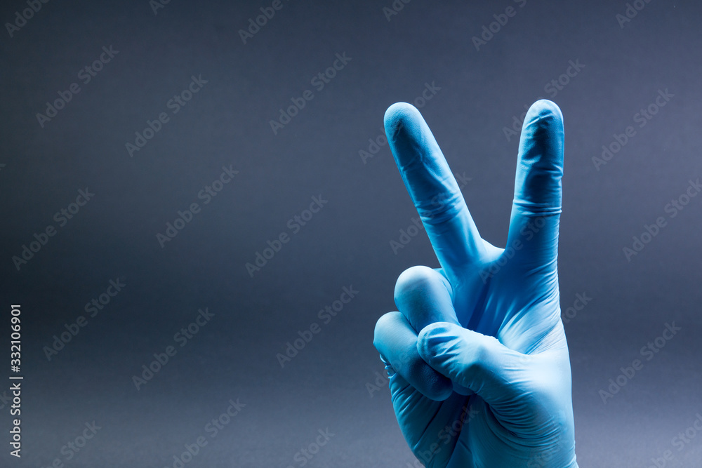 V sign is showed by right man hand in a blue medical glove on a black ...
