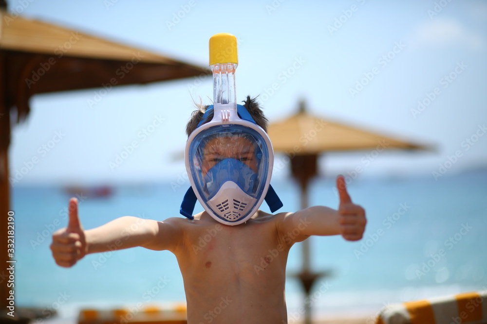 Portrait of a happy caucasian boy at the seaside wearing a diving mask ...