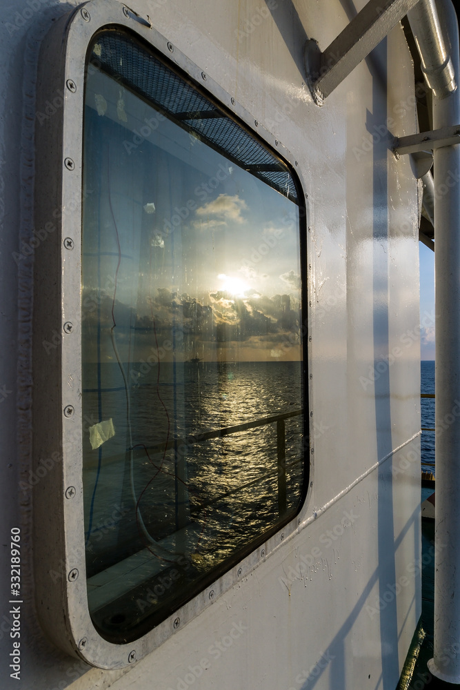 Sunrise reflection on a cabin galss window of a construction work barge ...