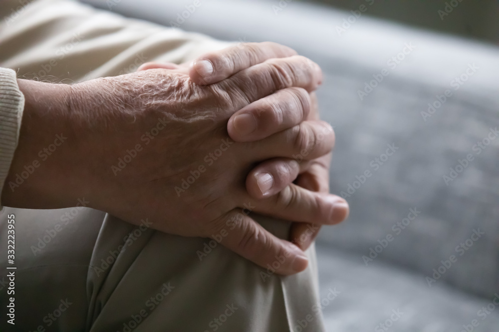 Old man sitting on couch close up view palms folded on knee. Concept of ...