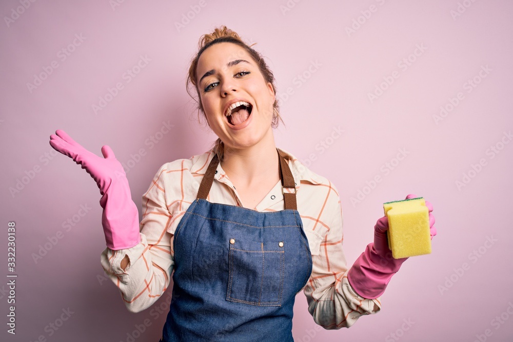 Beautiful blonde cleaner woman doing housework wearing arpon and gloves ...