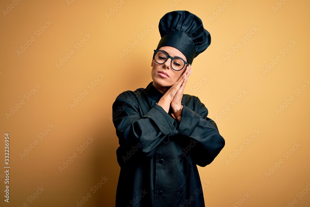 Young beautiful brunette chef woman wearing cooker uniform and hat over ...