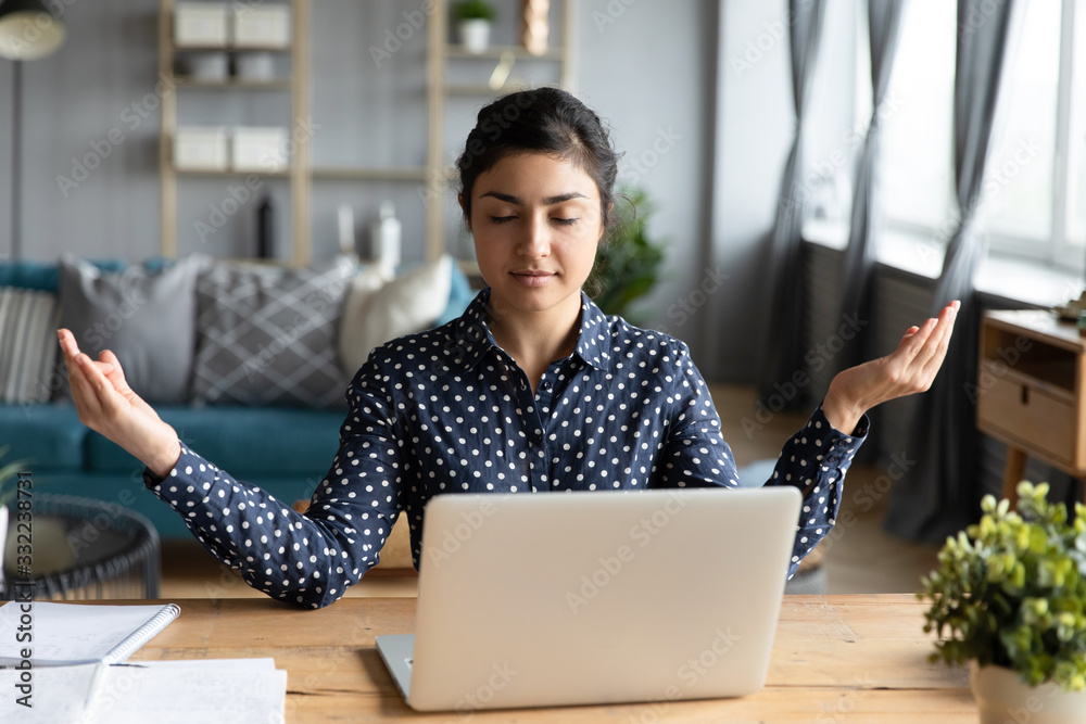 Calm Indian woman with closed eyes meditating at workplace, peaceful ...