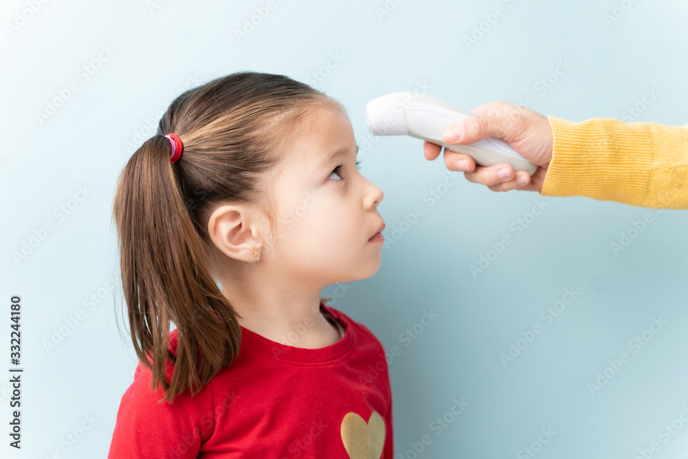 Profile view of an adult hand using a thermometer to check a little ...
