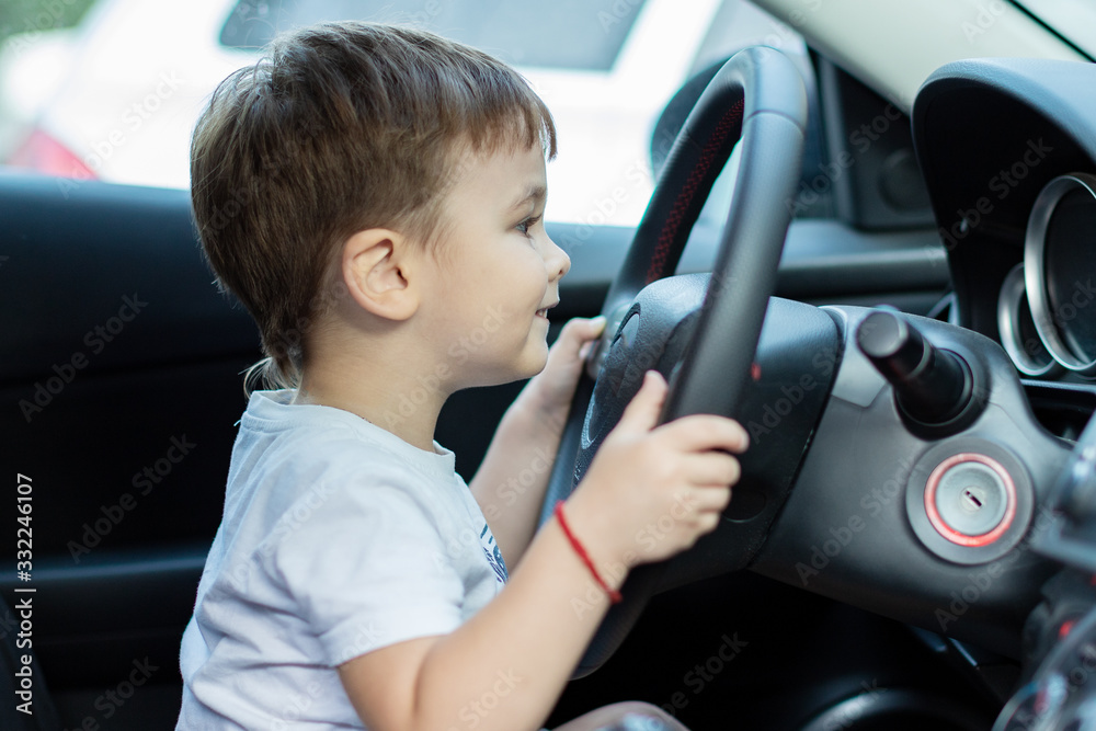 Cute little toddler boy driving big car holding steering wheel looking ...