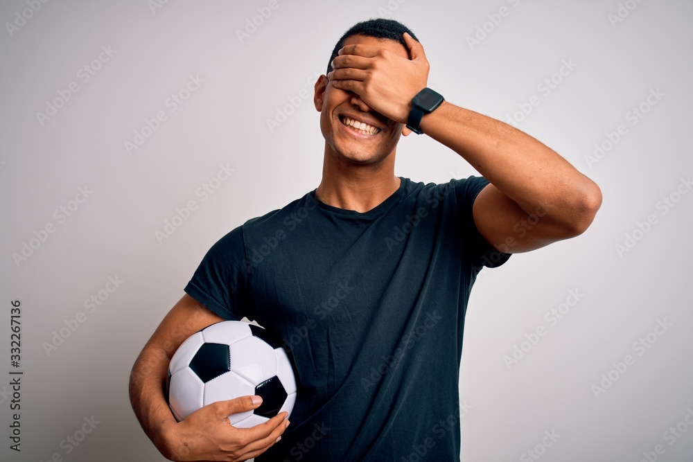 Handsome african american man playing footbal holding soccer ball over ...