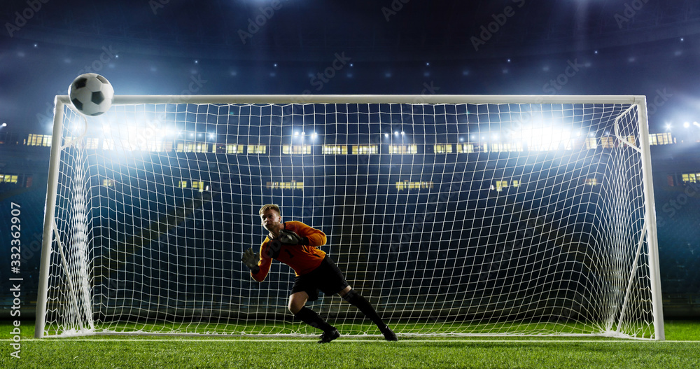Goalkeeper is trying to save from a goal on an empty soccer stadium. No ...