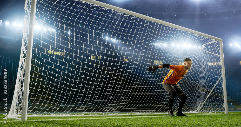 Goalkeeper is trying to save from a goal on an empty soccer stadium. No ...
