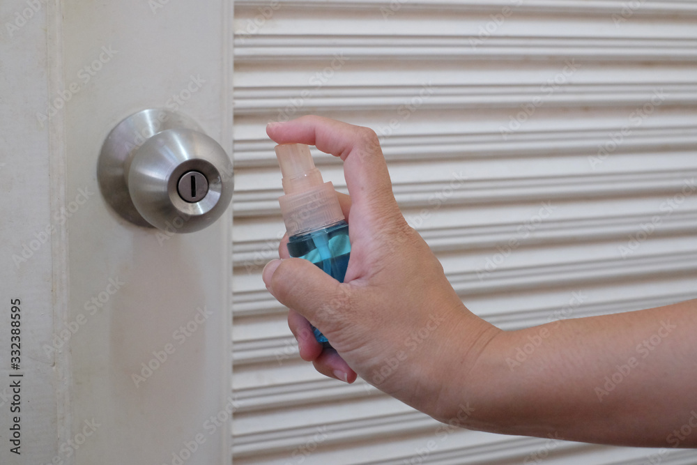 Close up hand using spray alcohol sanitize to disinfecting the door ...