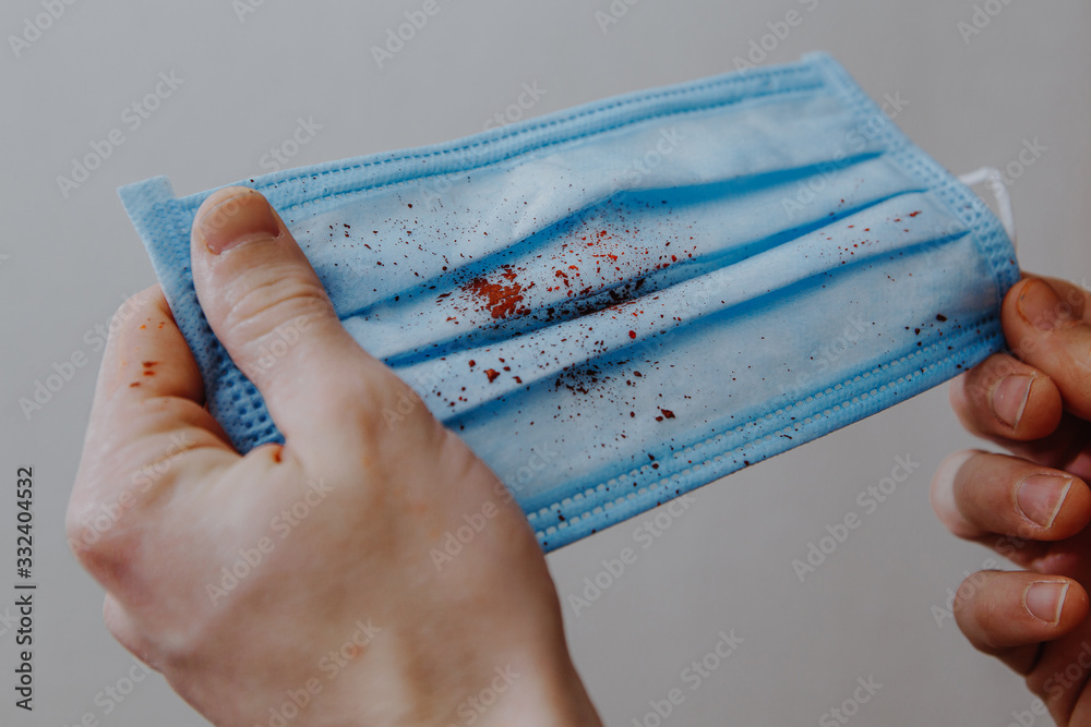 medical mask in the hands of a person splashed with blood from the ...