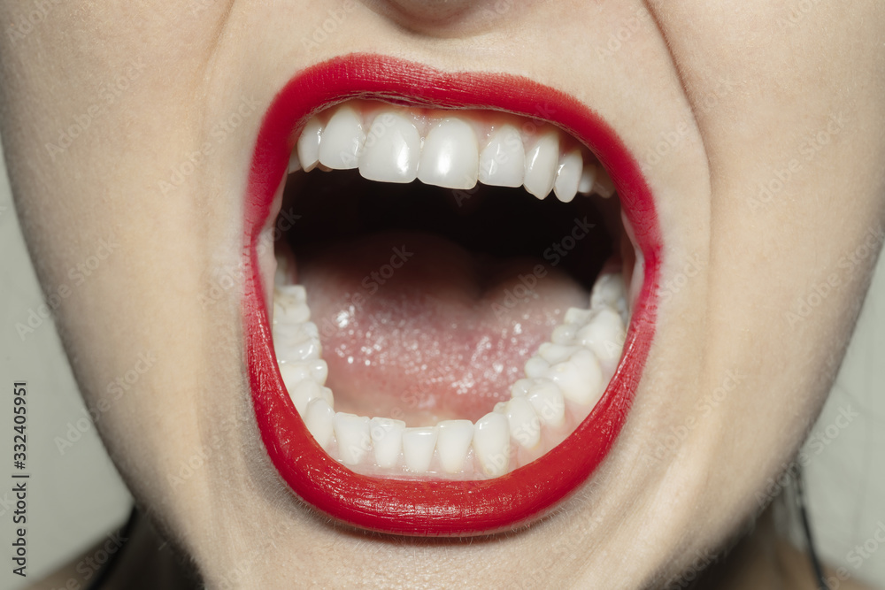 Angry screaming. Close-up shoot of female mouth with bright red gloss ...