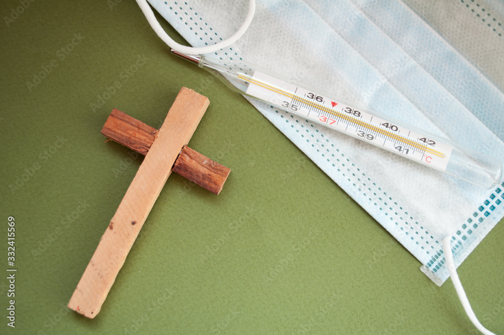 Medical mask, thermometer and wooden cross. We pray for patients dying ...