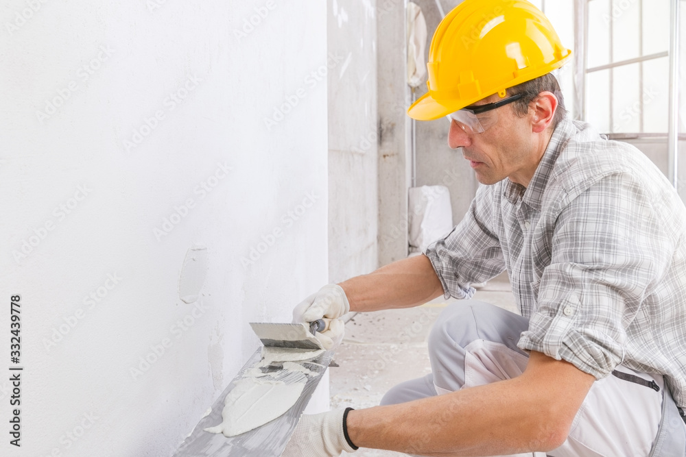 Builder using a trowel to add plaster to a wall Stock Photo | Adobe Stock