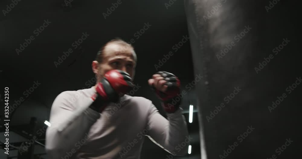 Angry boxer punching bag in gym - from below energetic male fighter ...