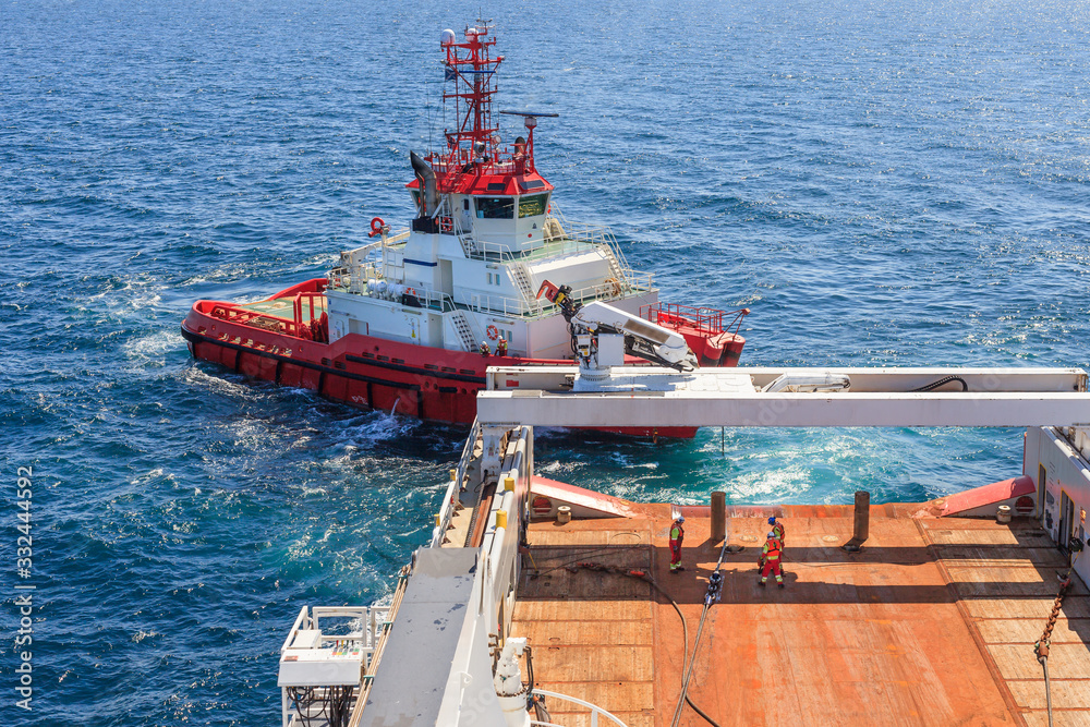 Offshore work with deck crew on deck and one small tugboat behind the ...