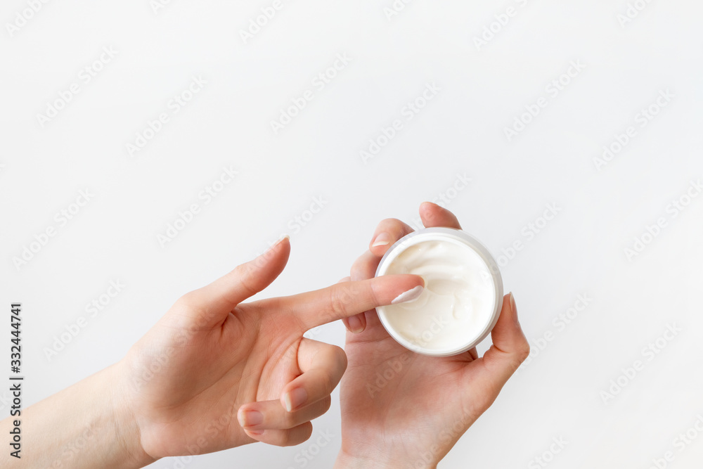 Girl finger applying moisturizer cream in white plastic container on ...