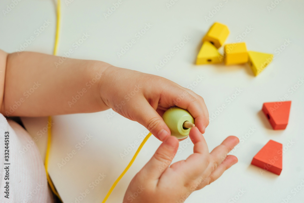 Child putting beads on a string. Bead stringing activity. Fine motor ...
