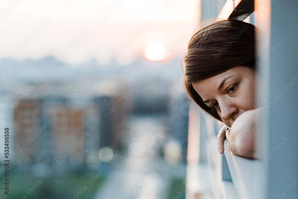 Young sad woman looking outside through balcony of an apartment ...