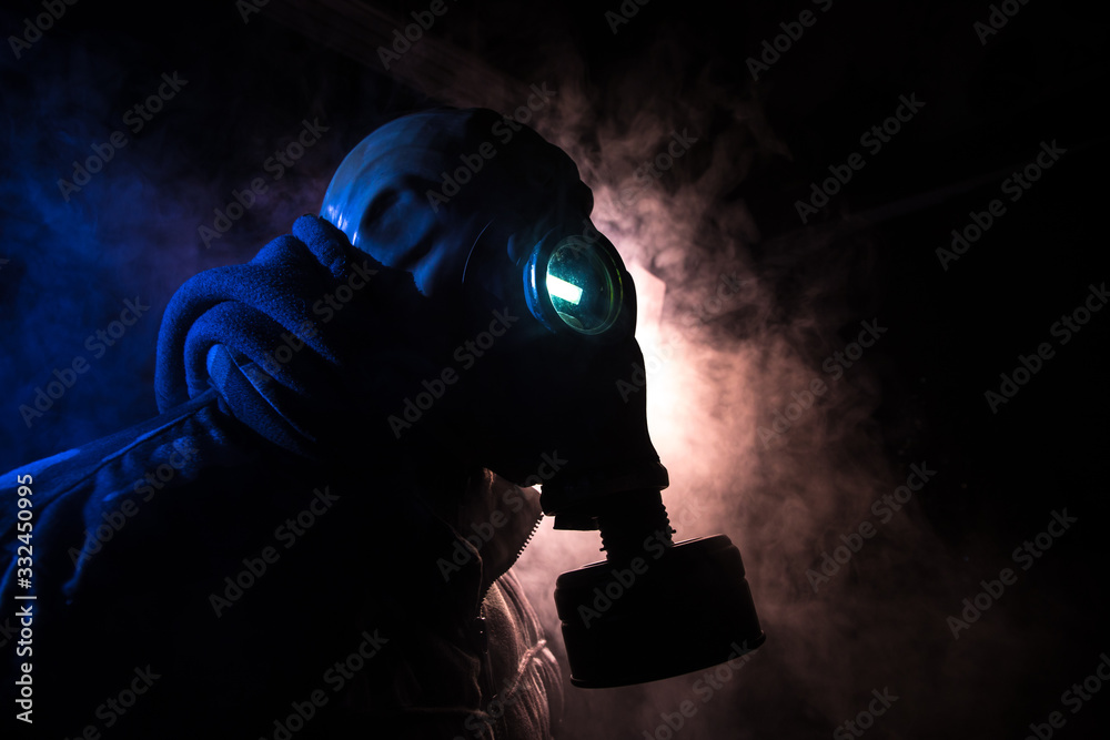 Gas mask with clouds of smoke on a dark background. Sign of radioactive ...