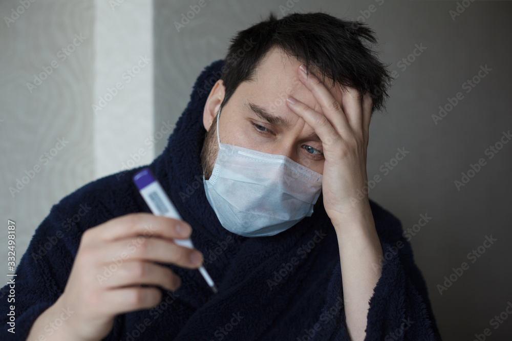 Worried man in medicine mask sit at home in dark gown and look at ...