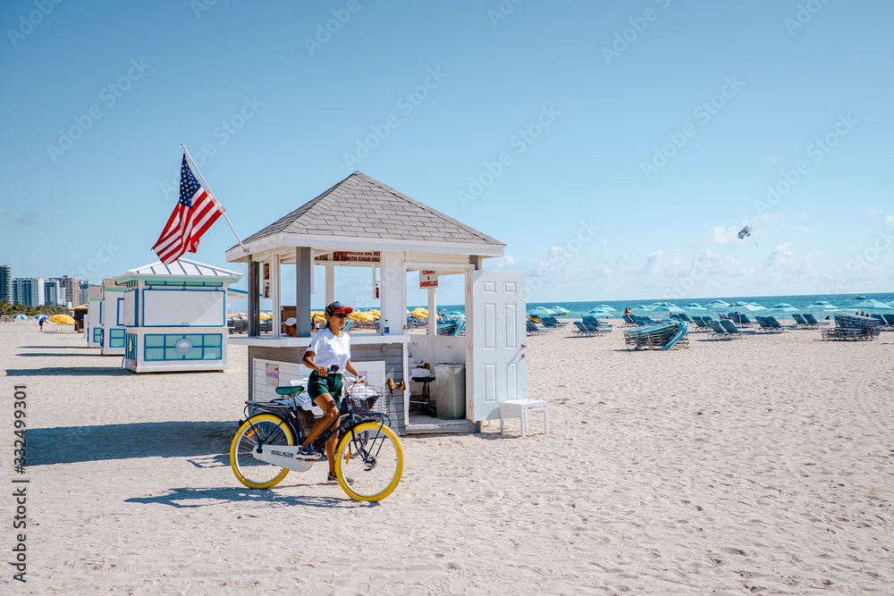 Miami beach Florida, young men on the beach with colorful lifeguard hut ...