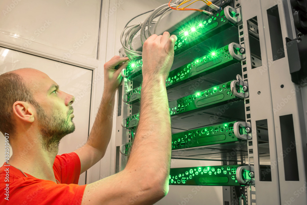 Technology concept. A man switches the wires in the computer equipment ...