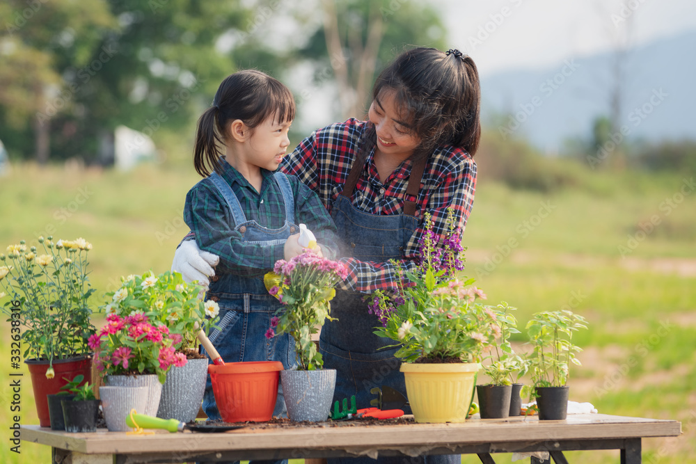 Asian little girl with mom planting and watering tree in nature. First ...