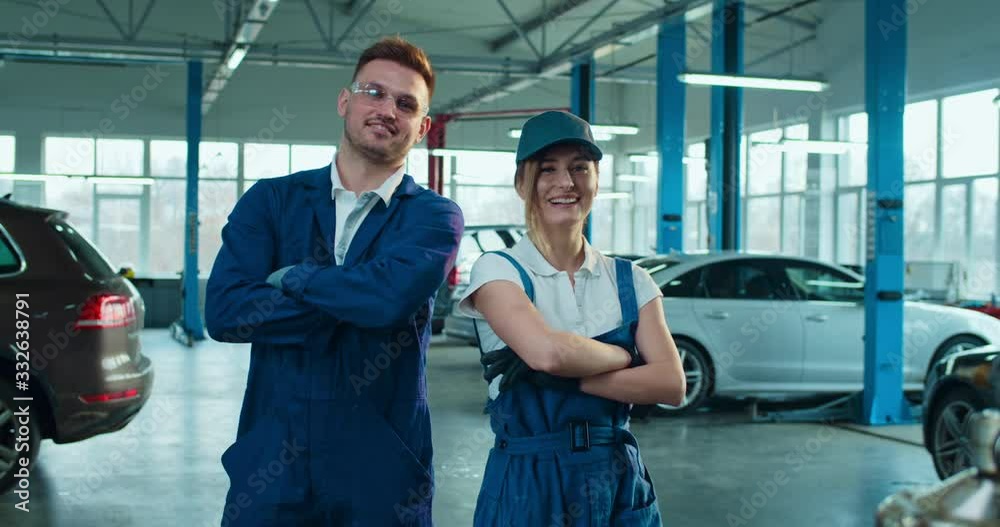 Couple of male and female auto mechanics in uniforms giving five to ...