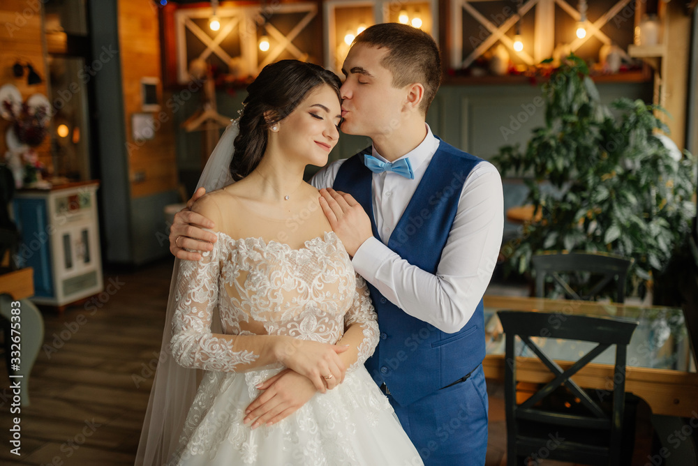 The groom hugs the bride by the shoulders and kisses her forehead. Love ...