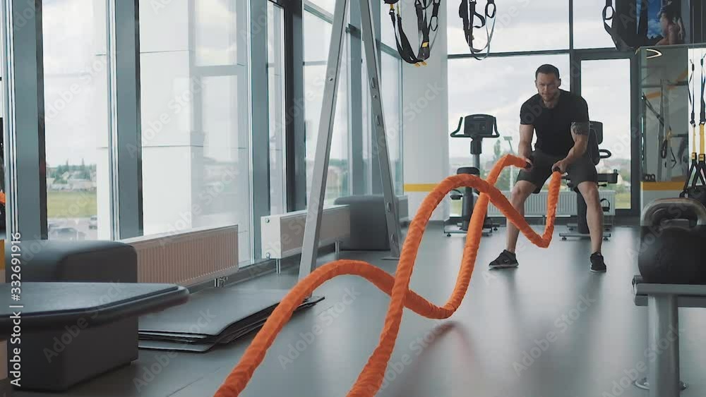 An athlete doing exercises on the rope in the gym with panoramic ...