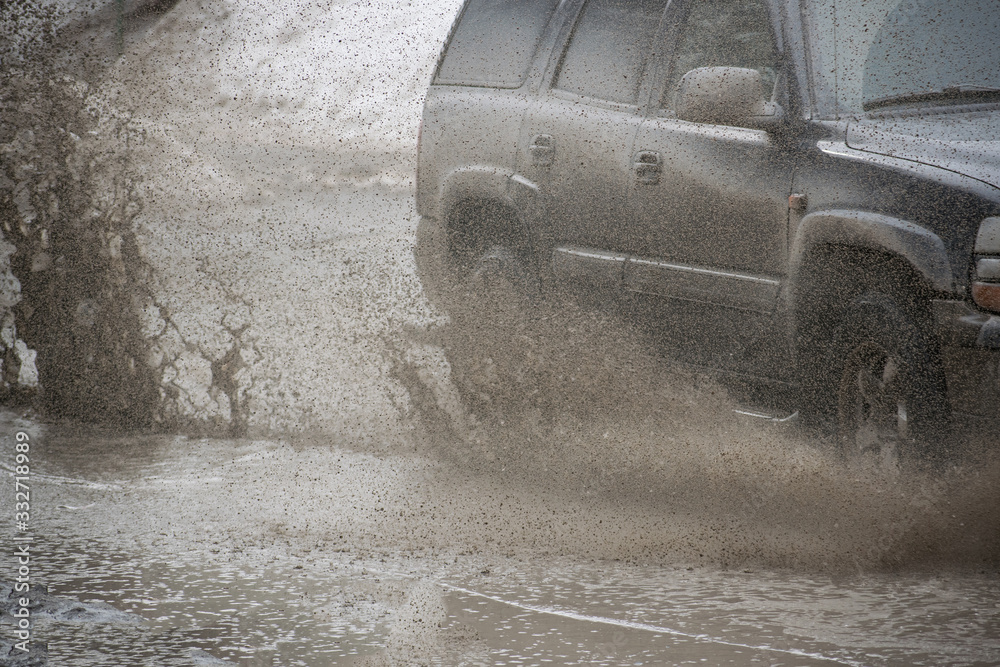 Car motion through big puddle of water splashes from the wheels on the ...