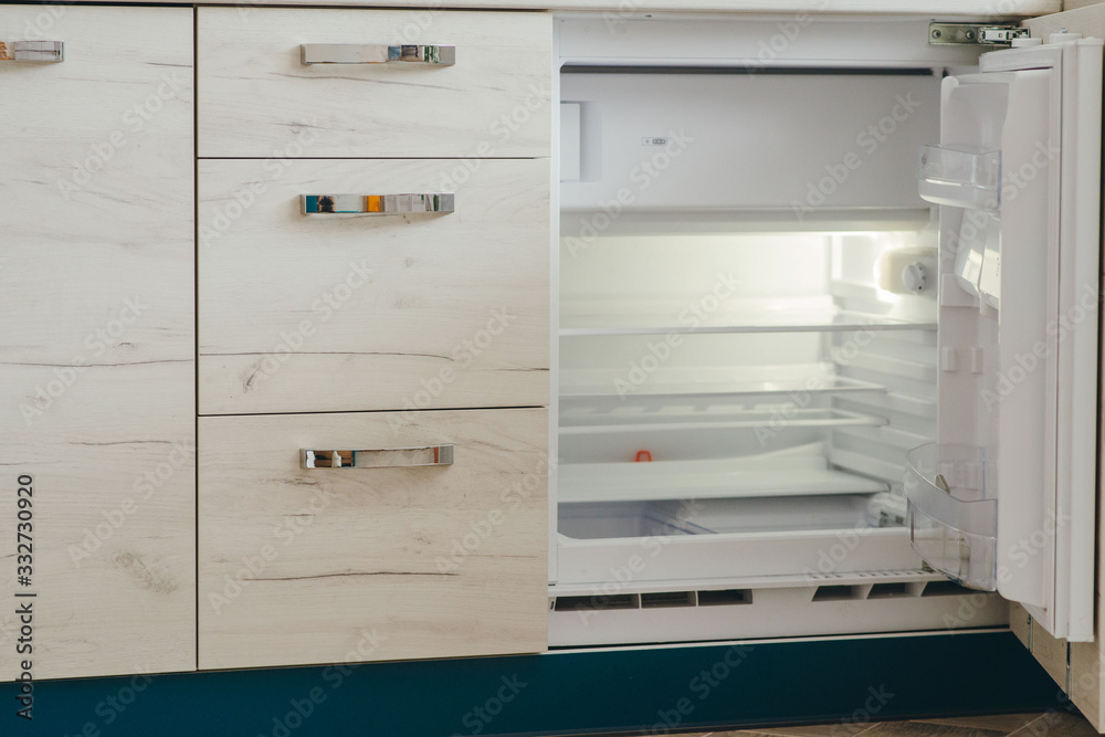 A picture of an open empty built-in fridge and a kitchen drawers on the ...