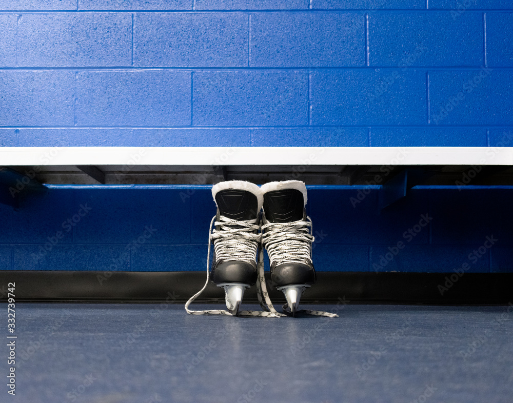 Hockey skates over floor in locker room with blue background and copy ...