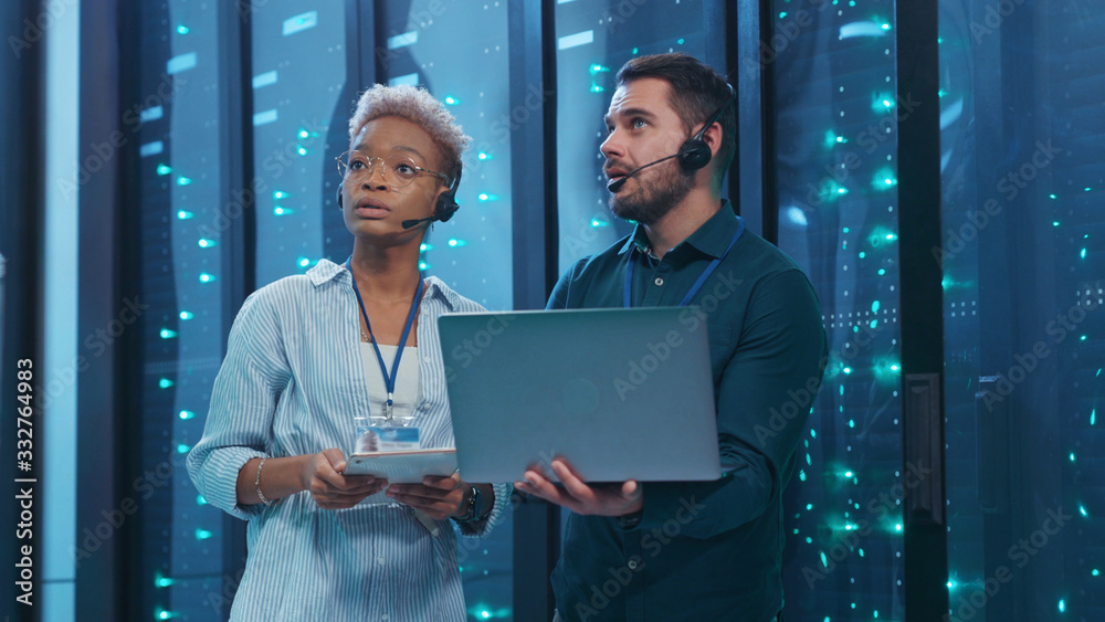 Data center male and female server technicians cooperating in server ...