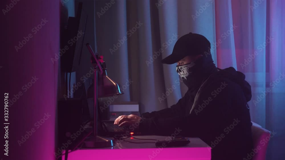 Male hacker sits at his desk and breaks into the system. Man in black ...