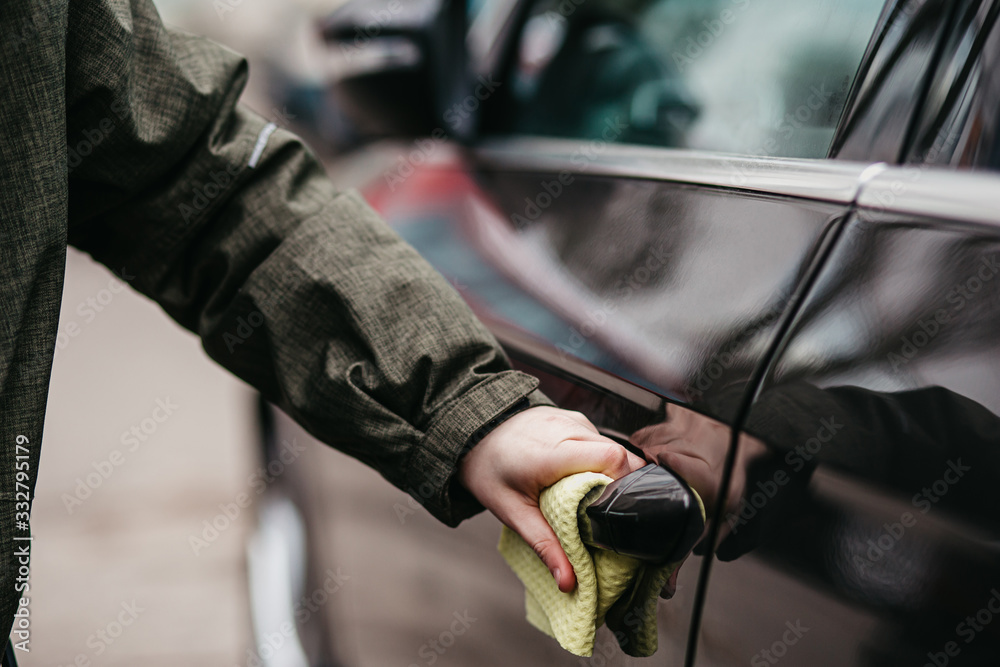 Man's hand disinfecting door handle of brown car by yellow disinfectant ...