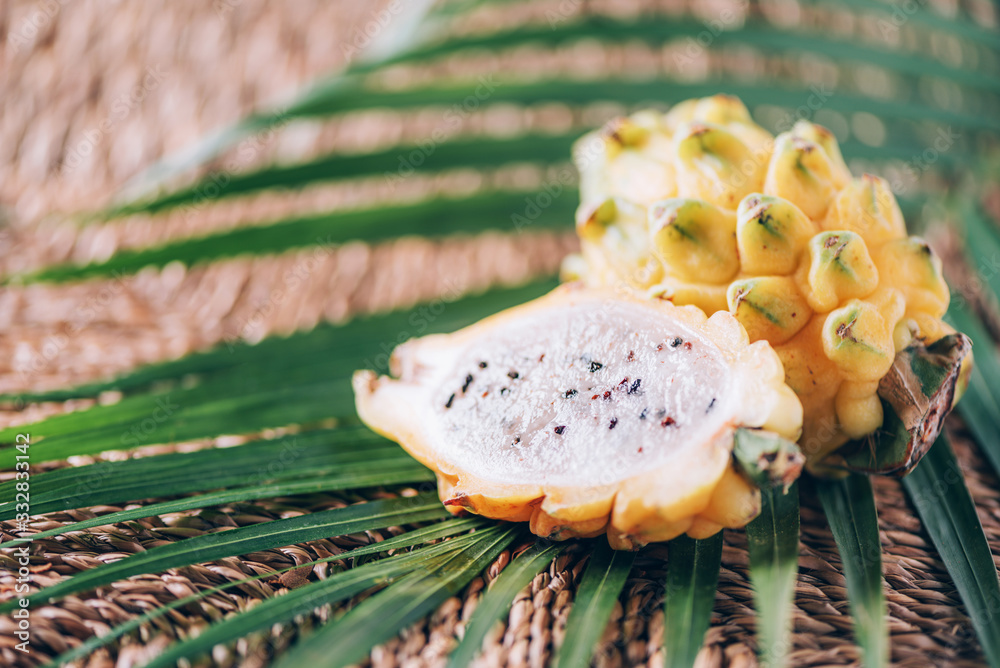 Yellow pitahaya pitaya or dragon fruit with palm leaves on rattan ...